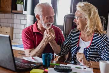 husband and wife sitting at a table with a laptop